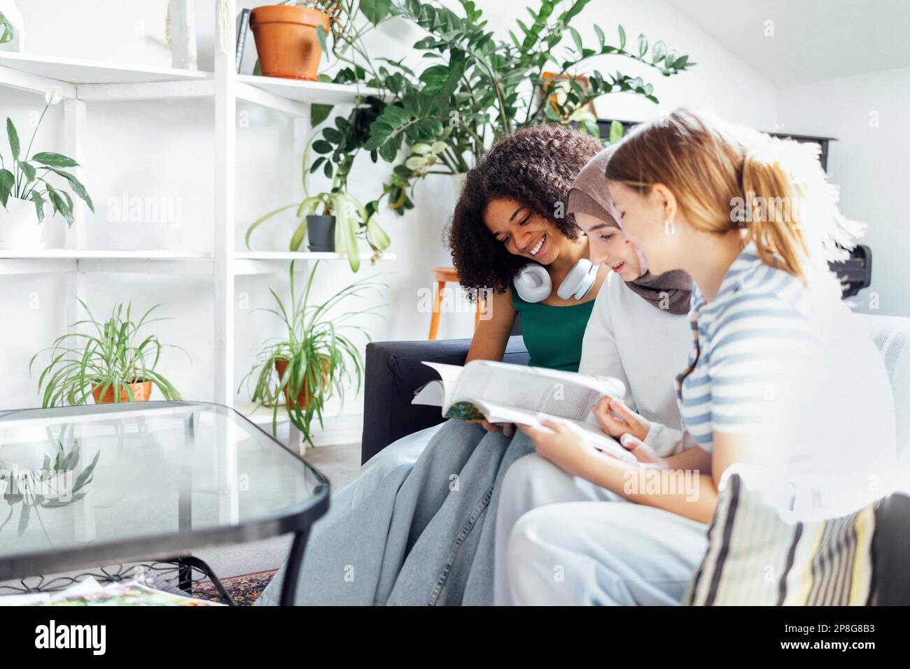 Three pretty female teenagers of different nationalities are reading a ...