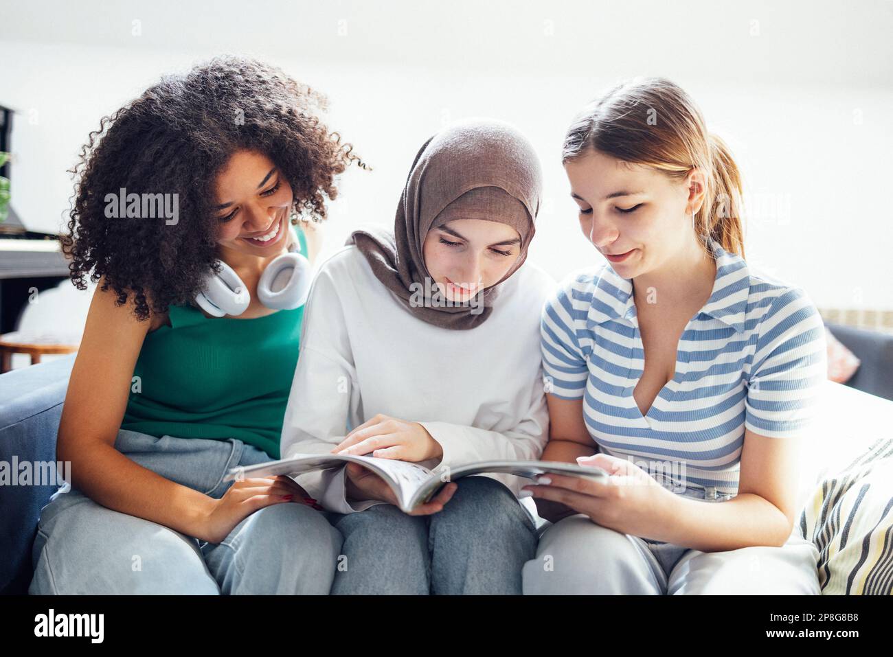 Three pretty female teenagers of different nationalities are reading a ...