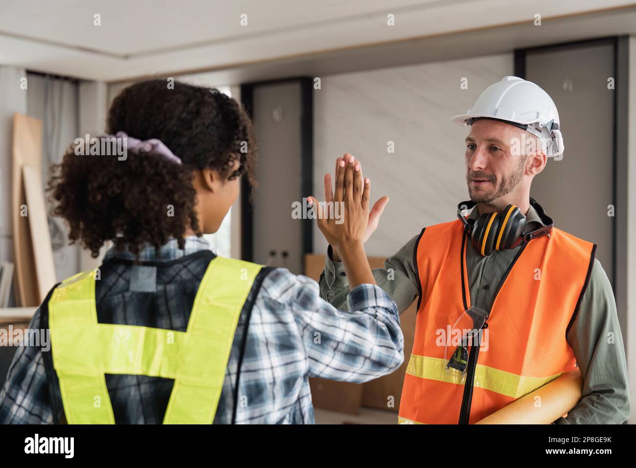 Construction engineer with blueprint making high five while standing on ...