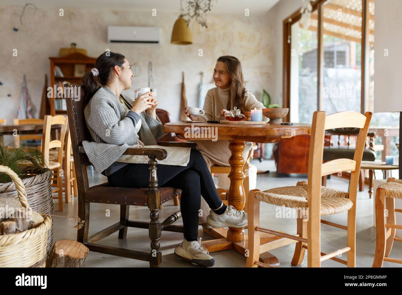 Two woman friends drinkind coffee or tea together. Talking, laughing ...