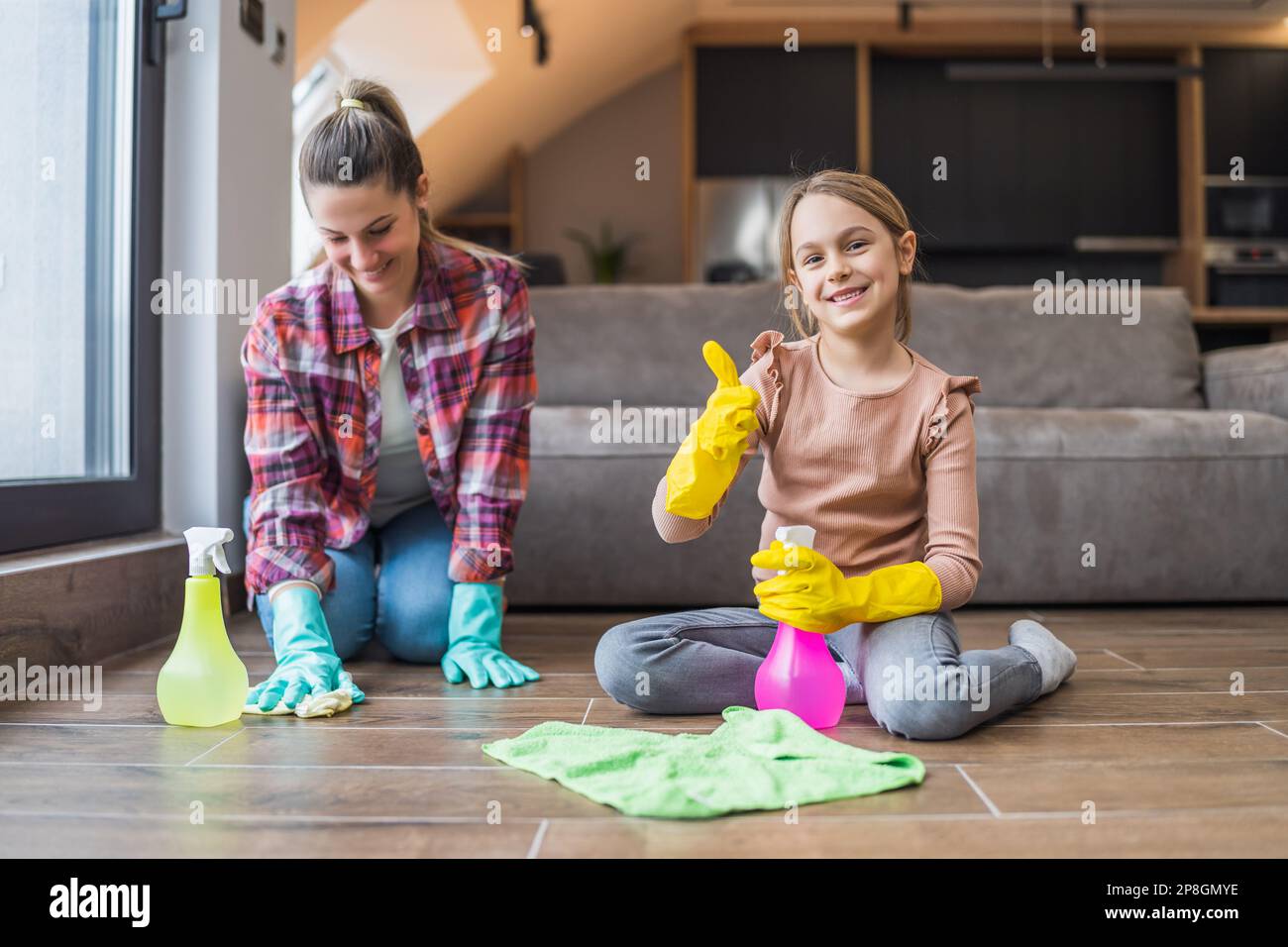 Happy daughter showing thumb up while cleaning house with her mother ...
