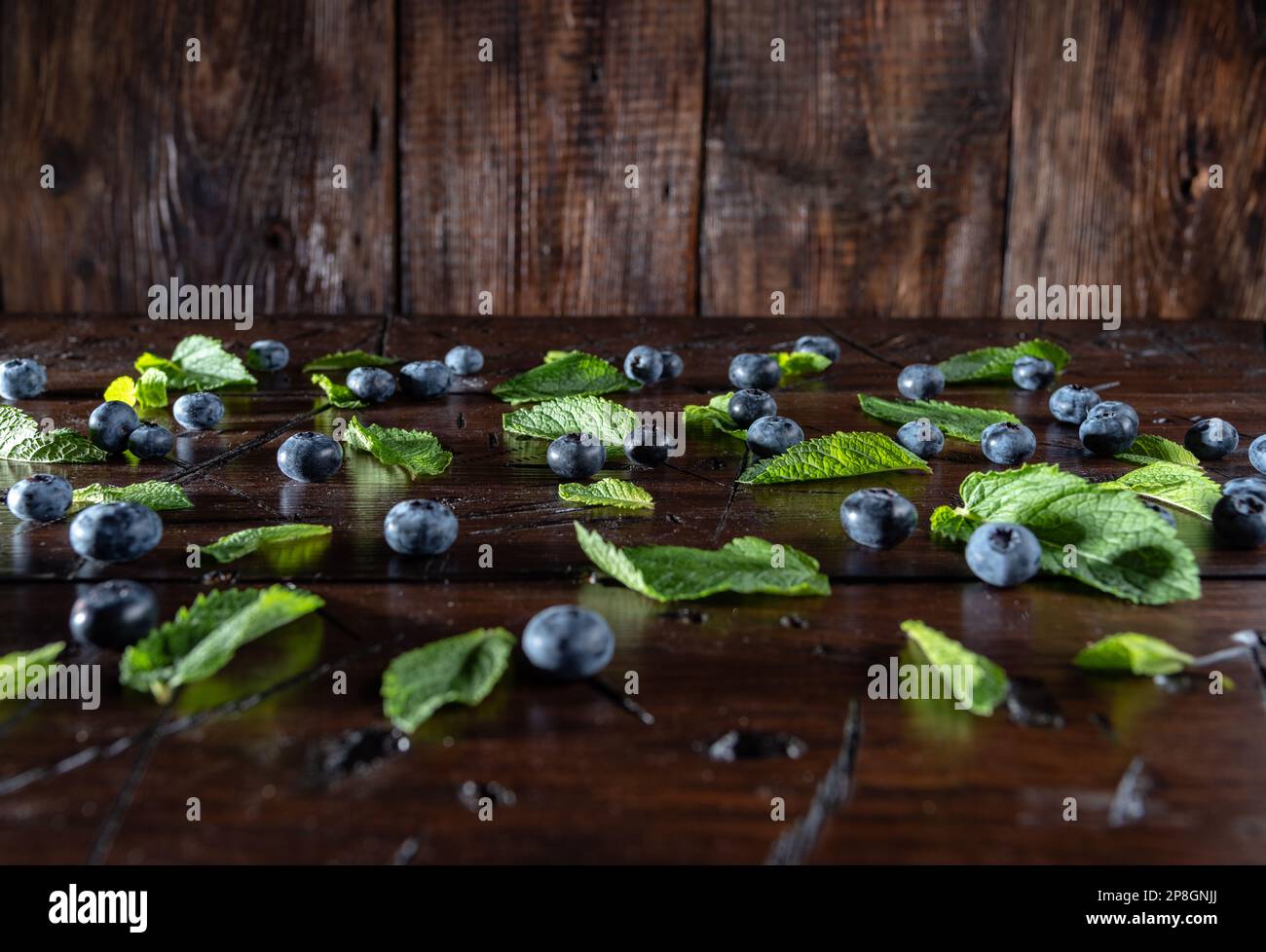 Blueberries are scattered on the table. Blueberries and leaves are ...