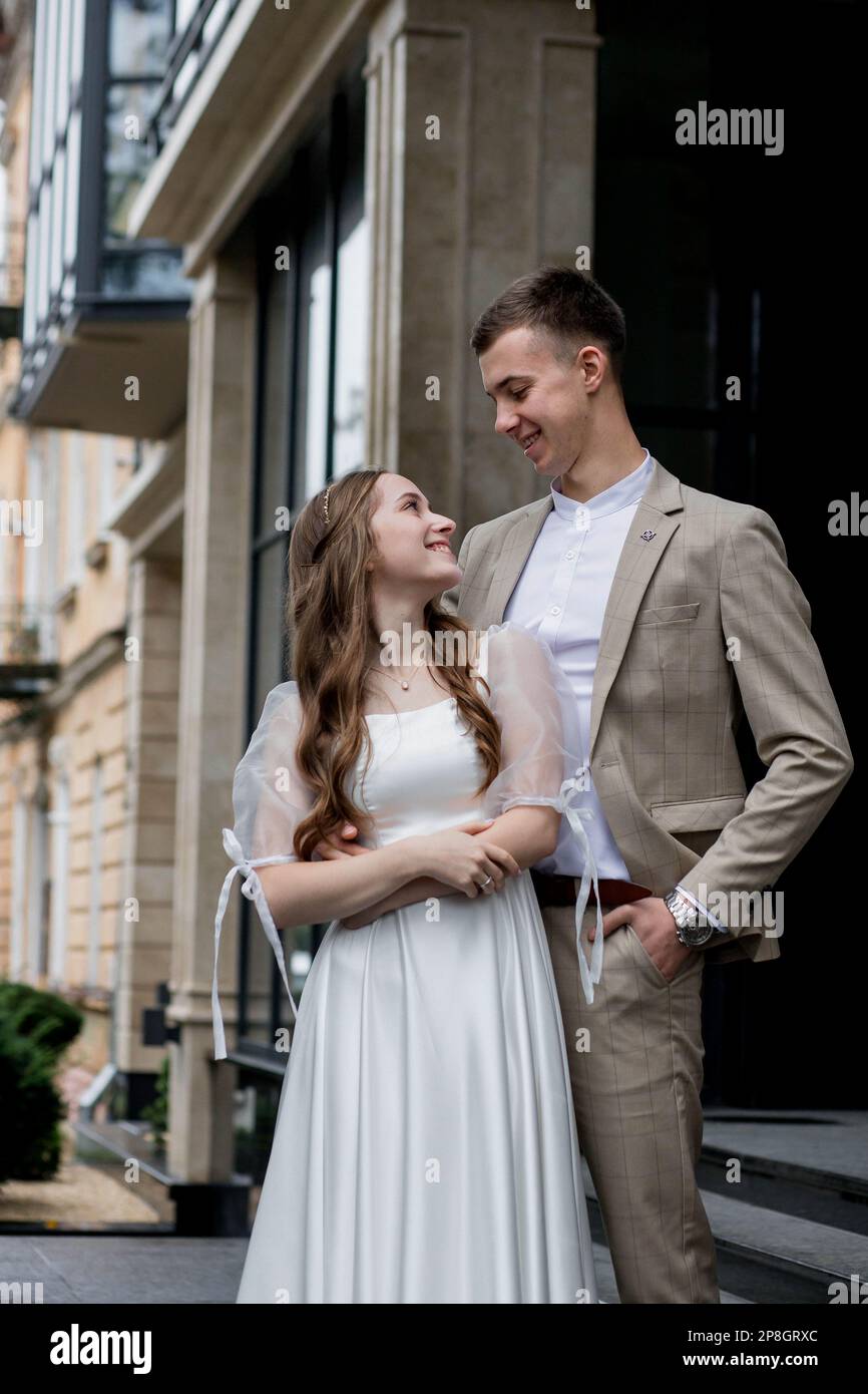 The bride looks at the groom with loving eyes. Smiling newlyweds look ...