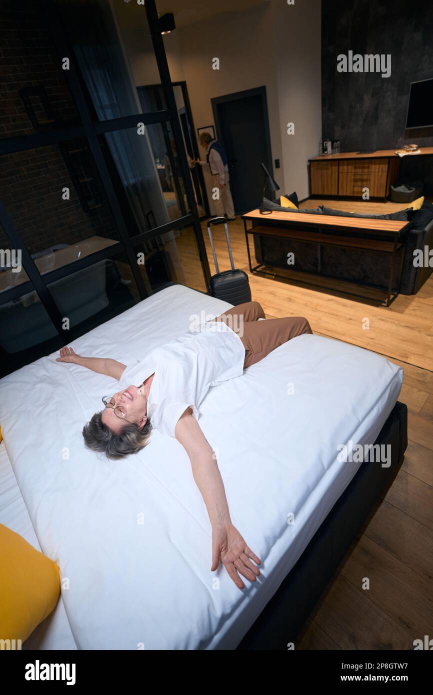 Happy traveling lady resting on bed with arms outstretched Stock Photo ...
