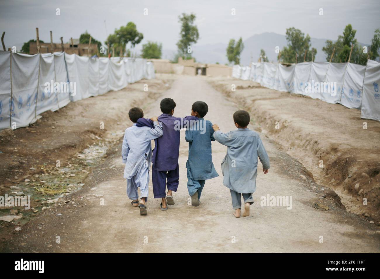 Pakistani children walk along a path in a refugee camp in Peshawar ...