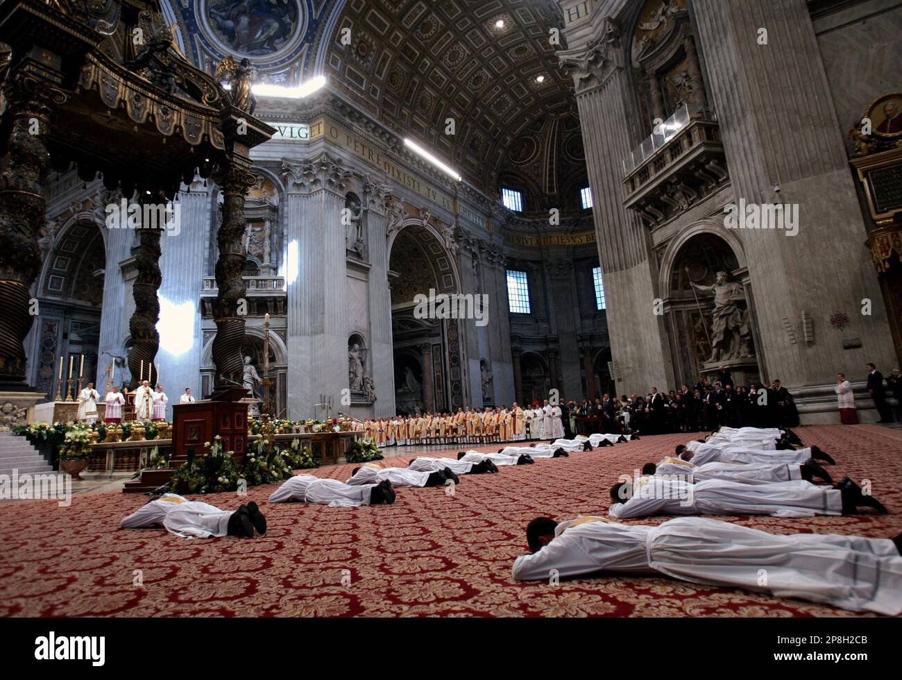 Newly ordained priests lay face down as they pray during a ceremony ...