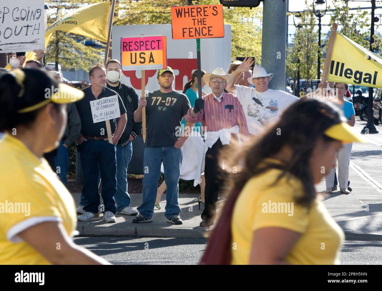 Protestors wave signs at yellow-clad marchers in an immigration rights ...