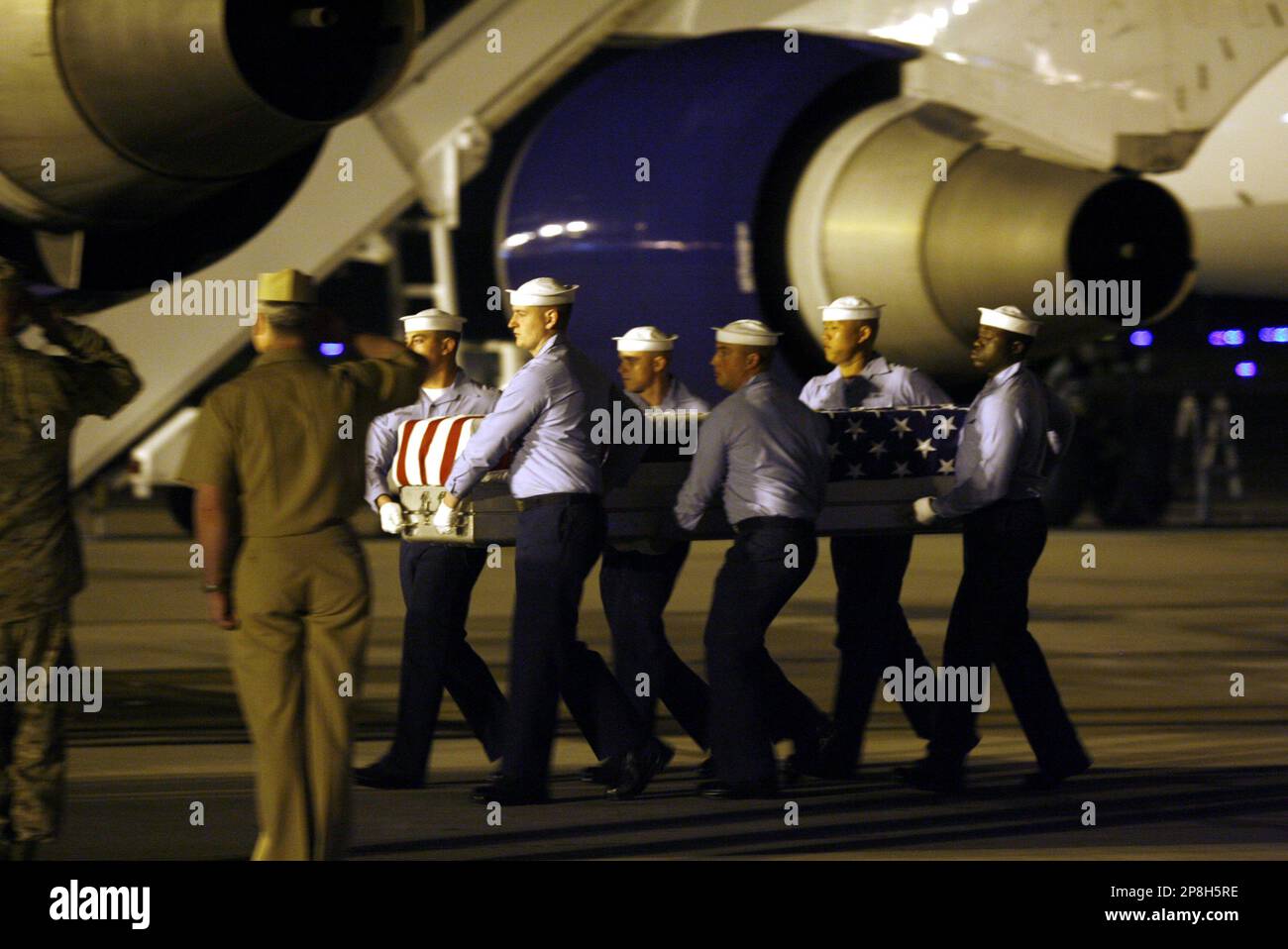 A Navy carry team carries the transfer case containing the remains of ...