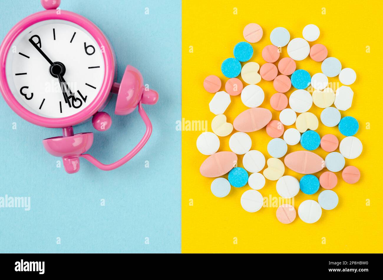 Colorful medical tablets with pink color alarm clock. Insomnia concepts ...