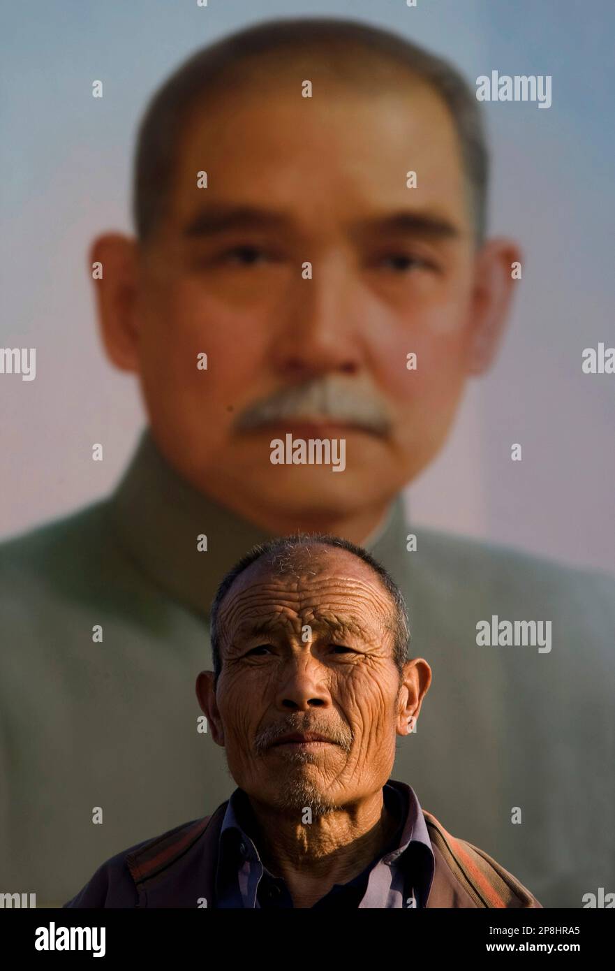 An elderly Chinese man pose near a portrait of the founding father of ...