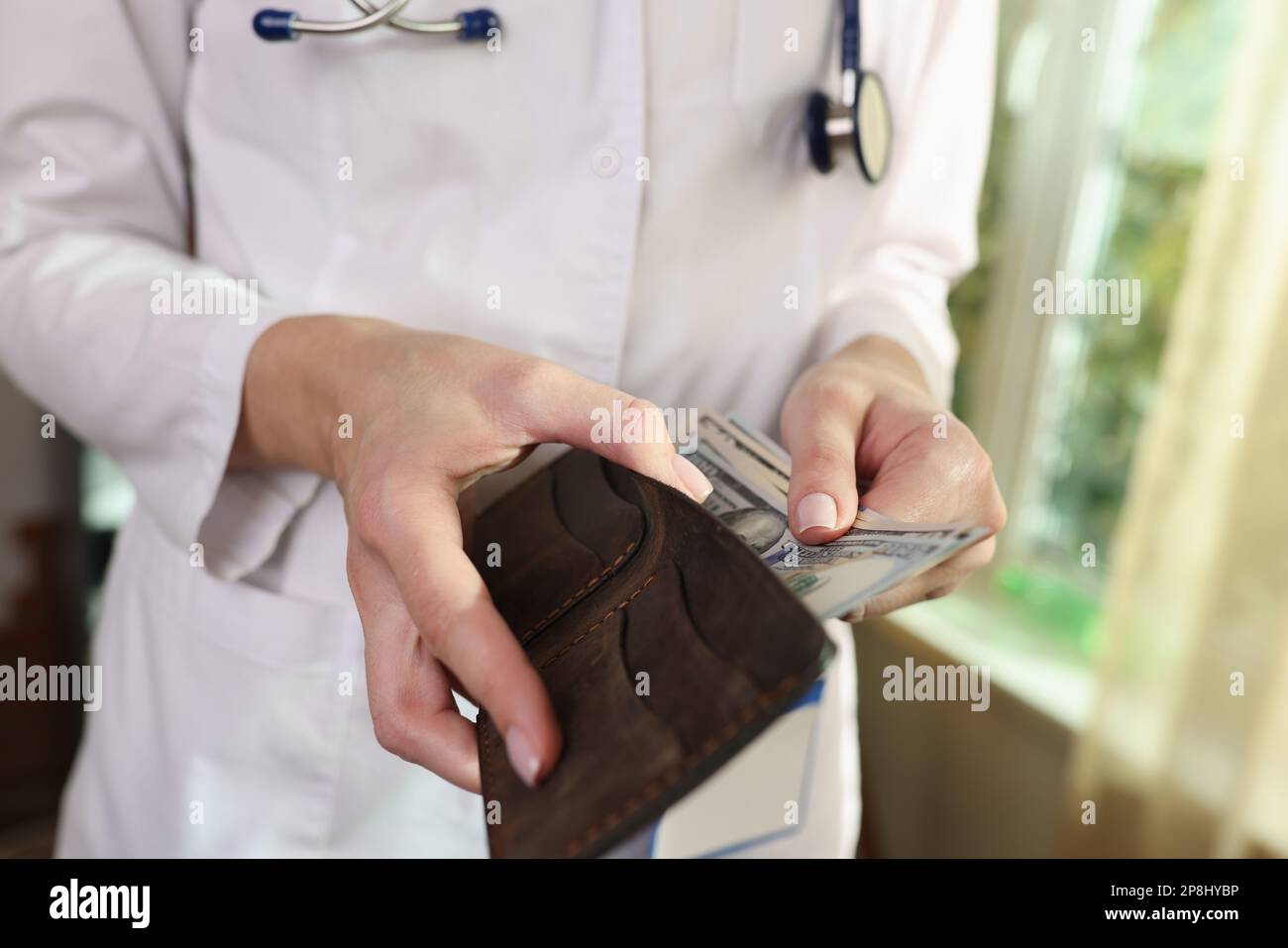 Female doctor hides money in wallet in hospital Stock Photo - Alamy