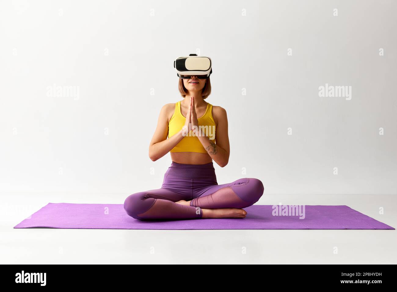 Flexible sportive young girl doing yoga exercises in VR headset glasses ...