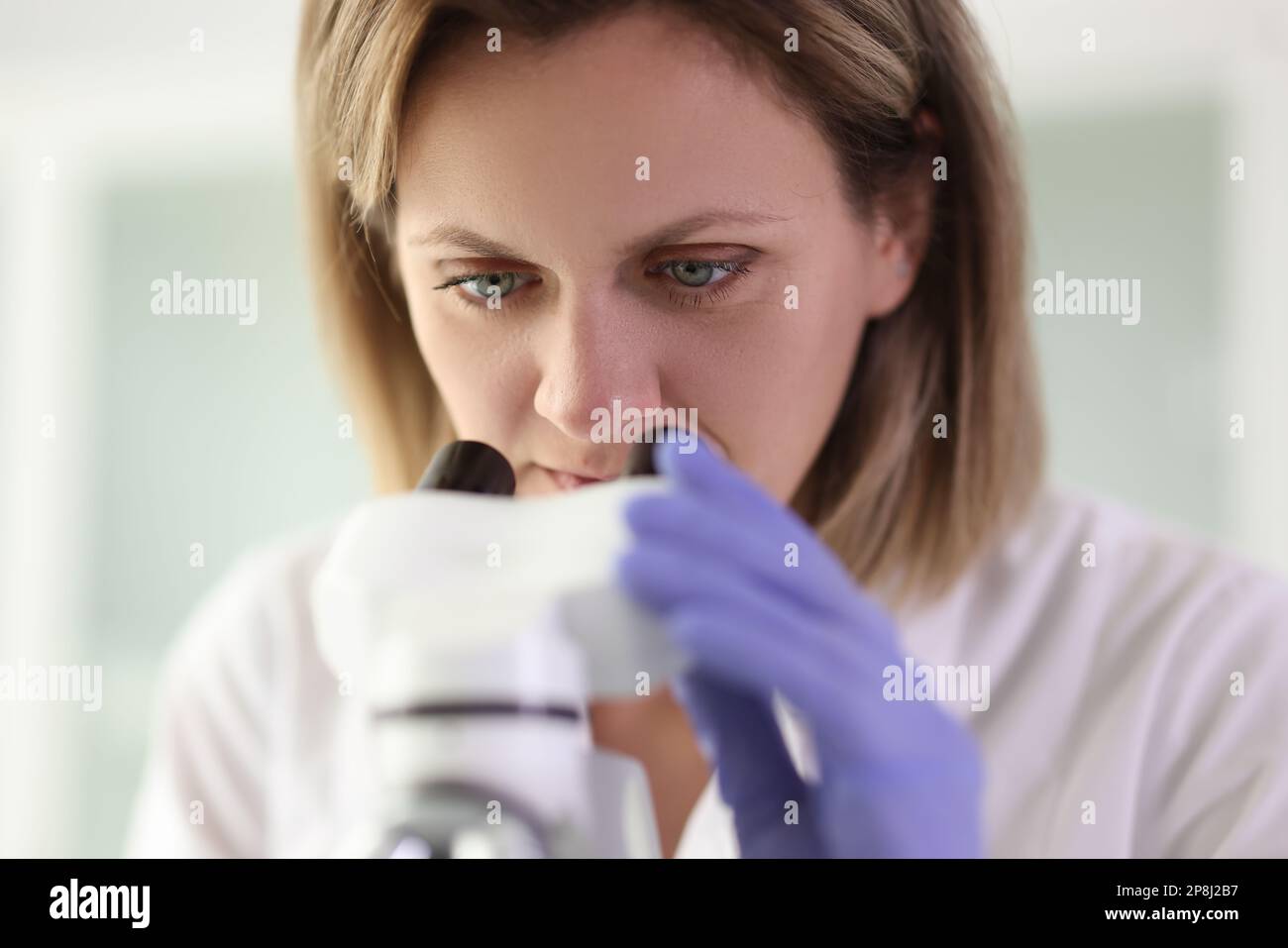 Close up of female scientist looks through microscope in research ...