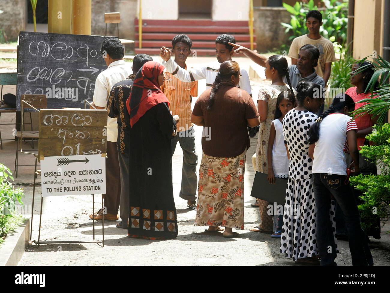Sri Lankans wait in queue for voting outside a polling booth in Colombo ...
