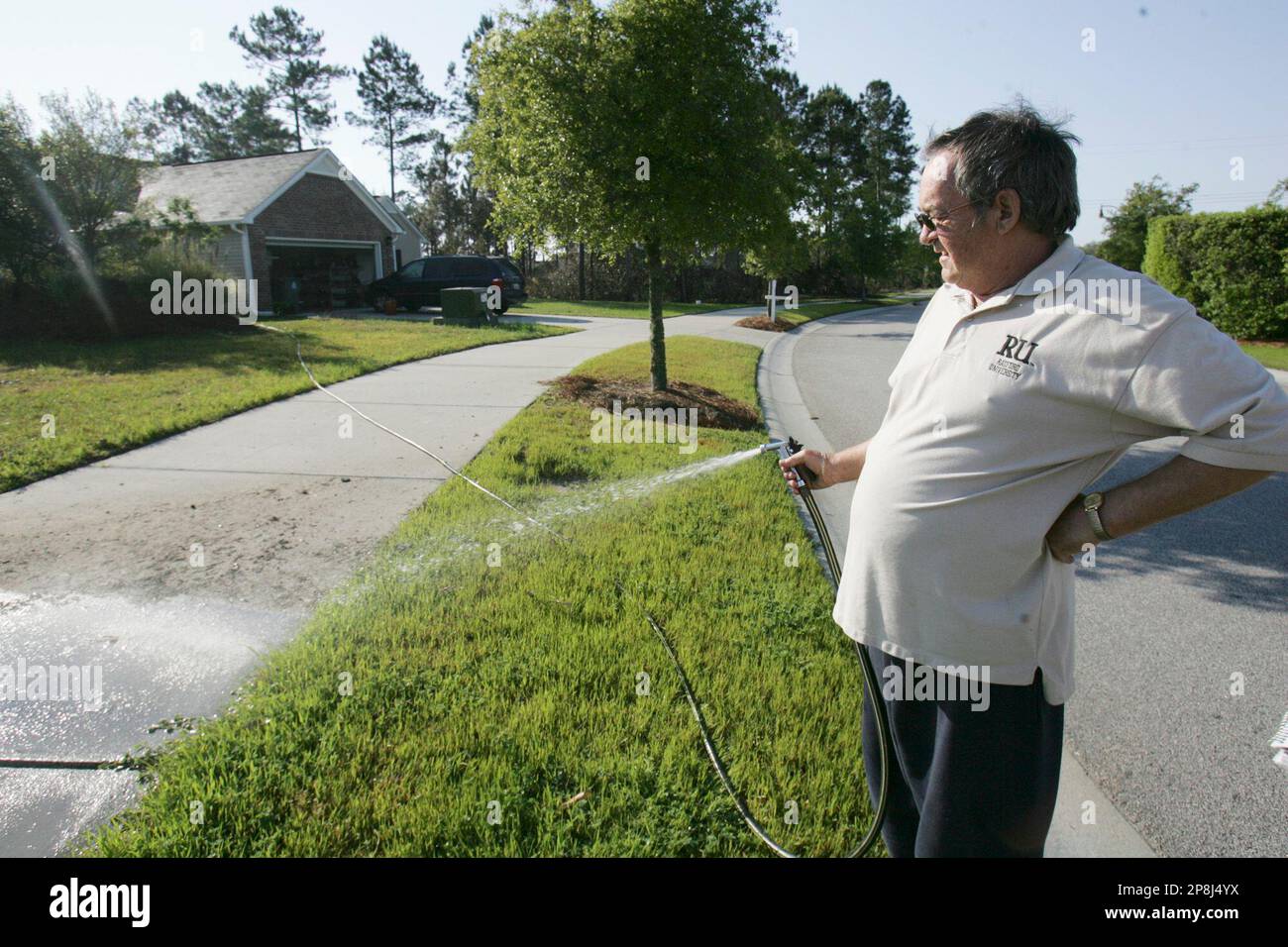 Robert Whitlock uses his garden hose to keep his yard moist in a ...