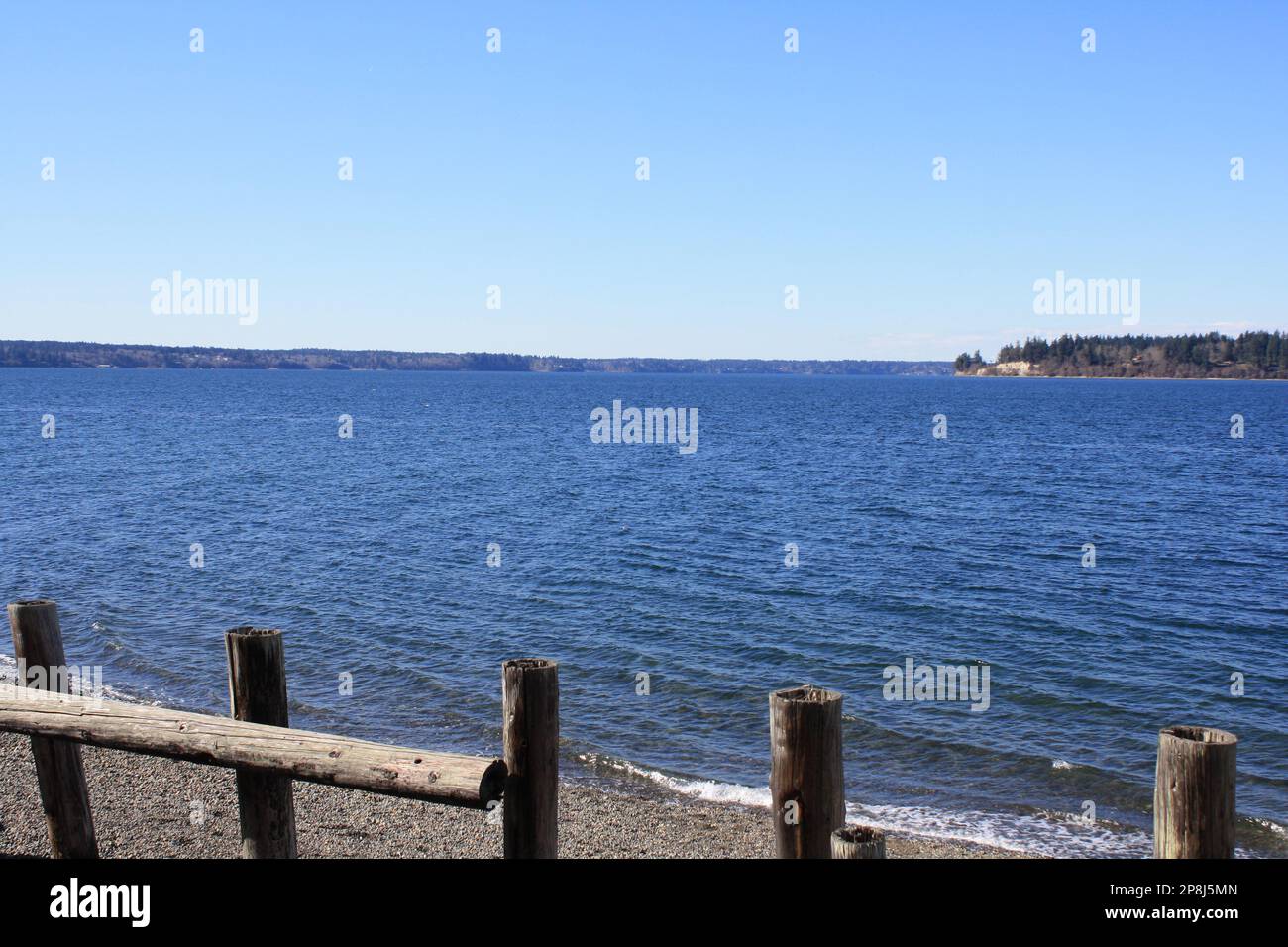 Beach-side view of ocean with fenceposts and island in distance Stock ...
