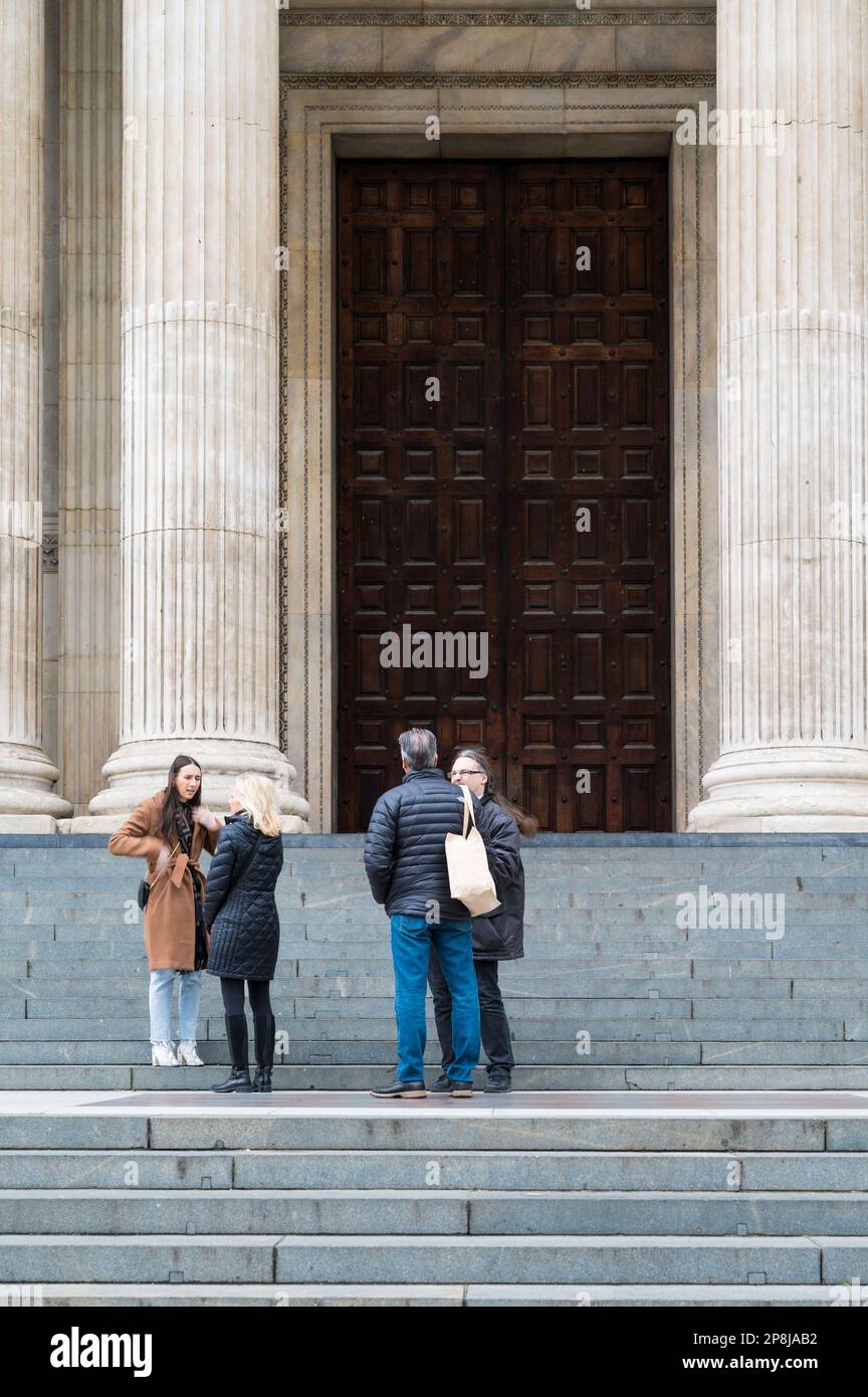 Groups of two women and two men stand in conversation in front of the ...