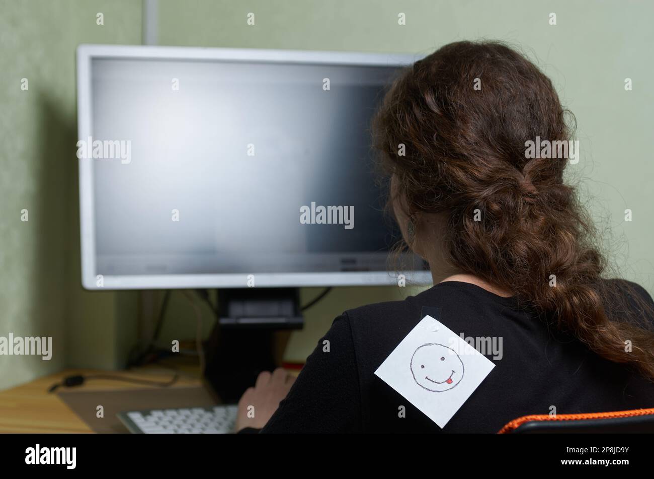 A woman with an April Fool's note on her back works at a computer Stock ...