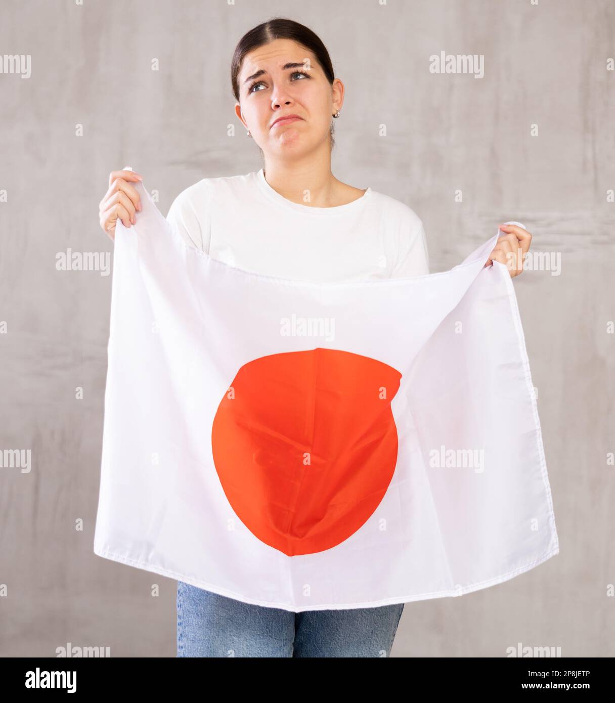 Sad young woman holding Japan flag against unicoloured background Stock ...