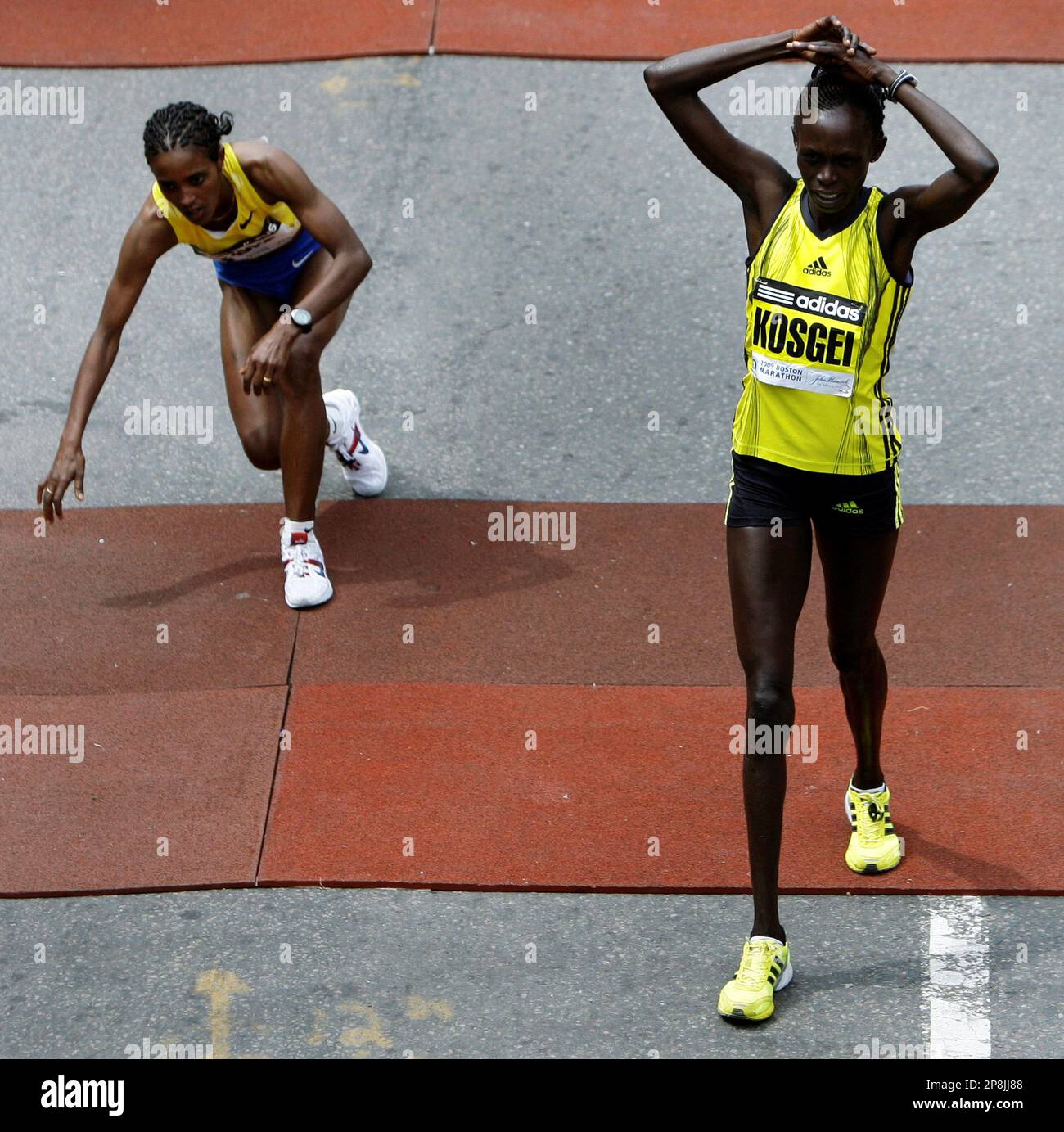 Dire Tune of Ethiopia, left, collapses after crossing the finish line ...