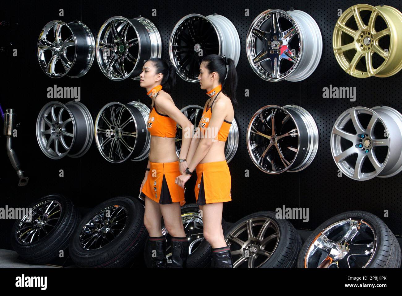 Models stand in front of wheels at Dunlop exhibition booth at the ...
