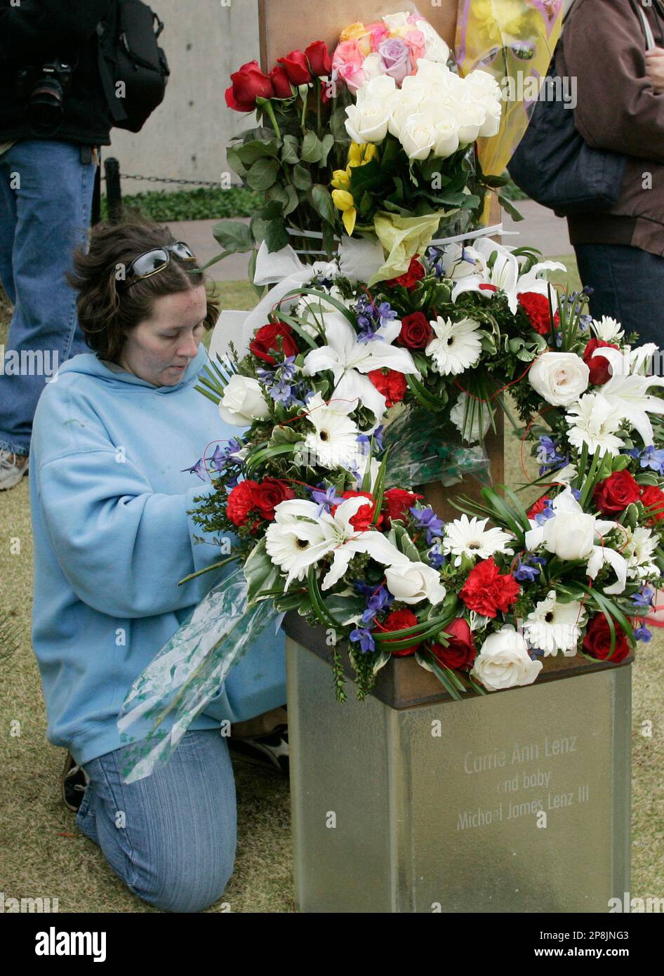 Reanna Burns adjusts the flowers at the chair of her cousin, Carrie Ann ...