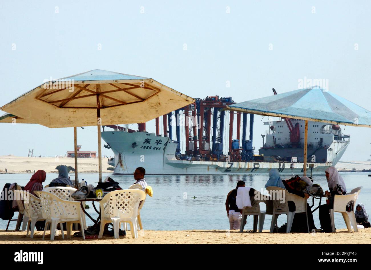 Egyptian holiday makers rest on the shores of the Suez Canal as the ...