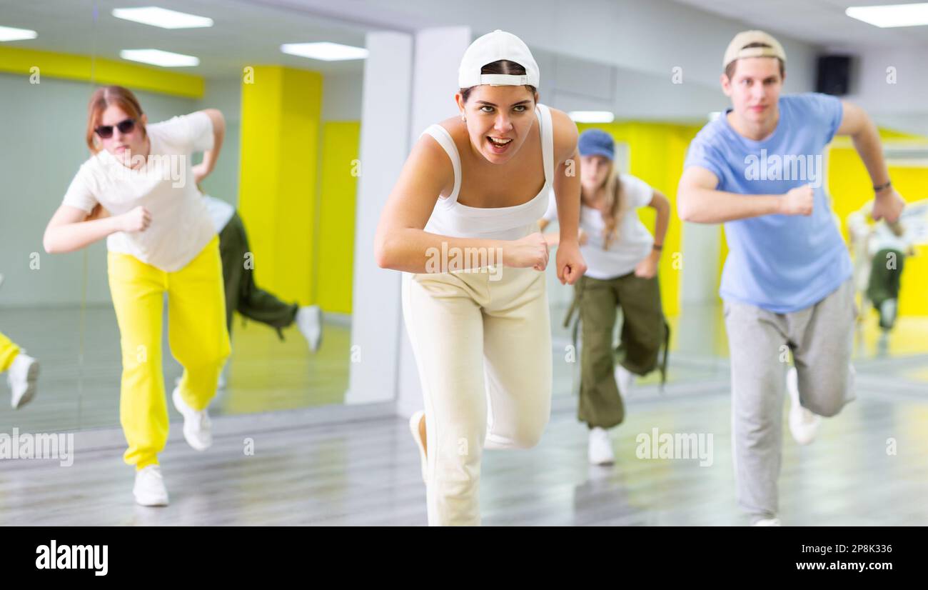 Energetic fit teens tilting body forward while standing on one leg in ...
