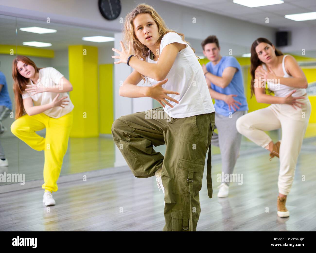 Class of confident young people practicing new dance moves together ...
