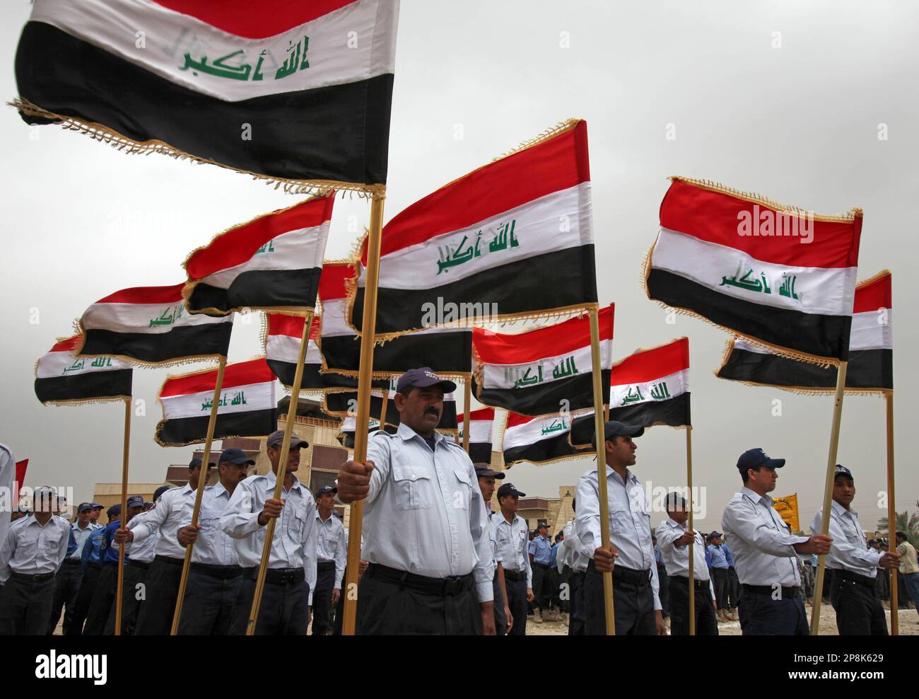 Iraqi police cadets hold the Iraqi flag as they stand in formation ...