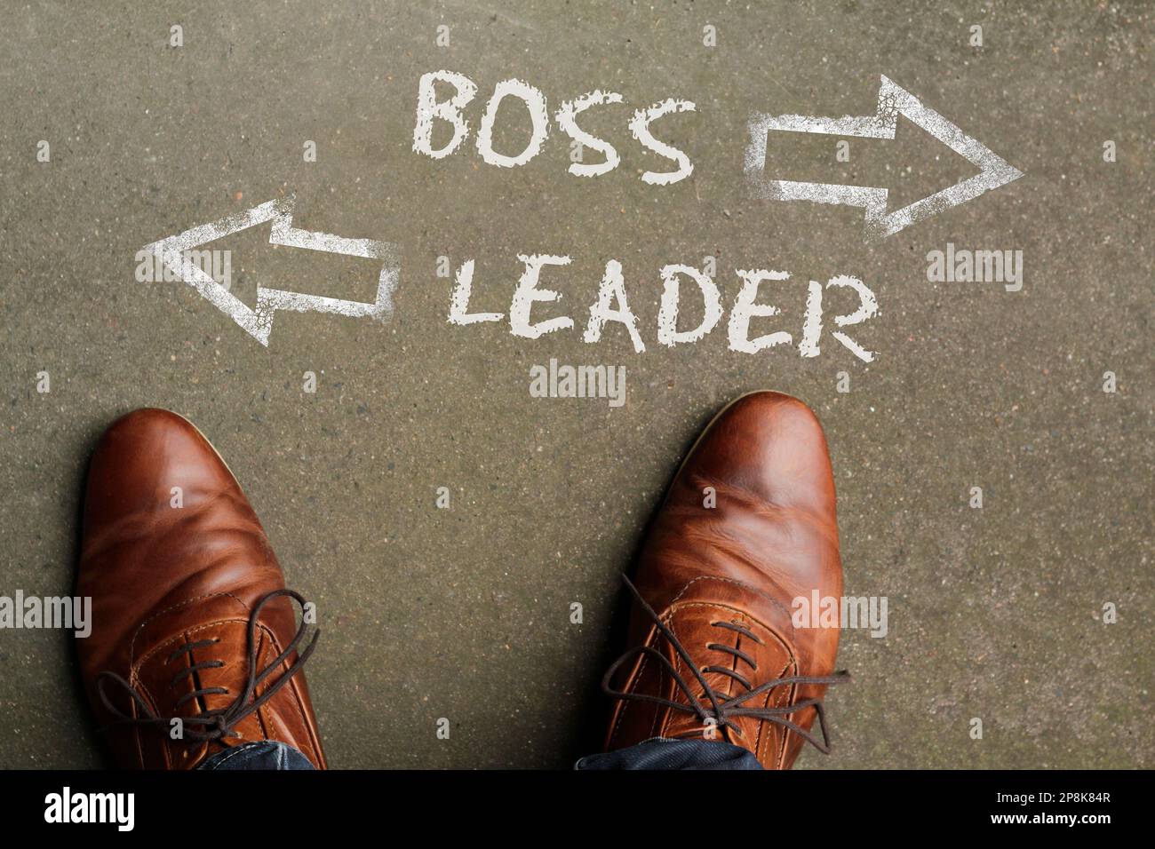 Man looking down at the words "Boss" and "Leader" chalked onto the ...