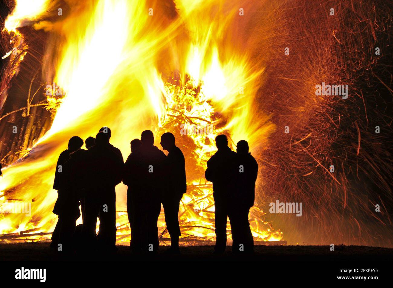 People stand in front of an Easter bonfire, an old German ethnic custom ...