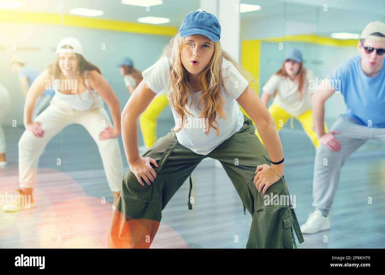 Teenage girl in cap training breakdance Toprock moves in dance hall ...