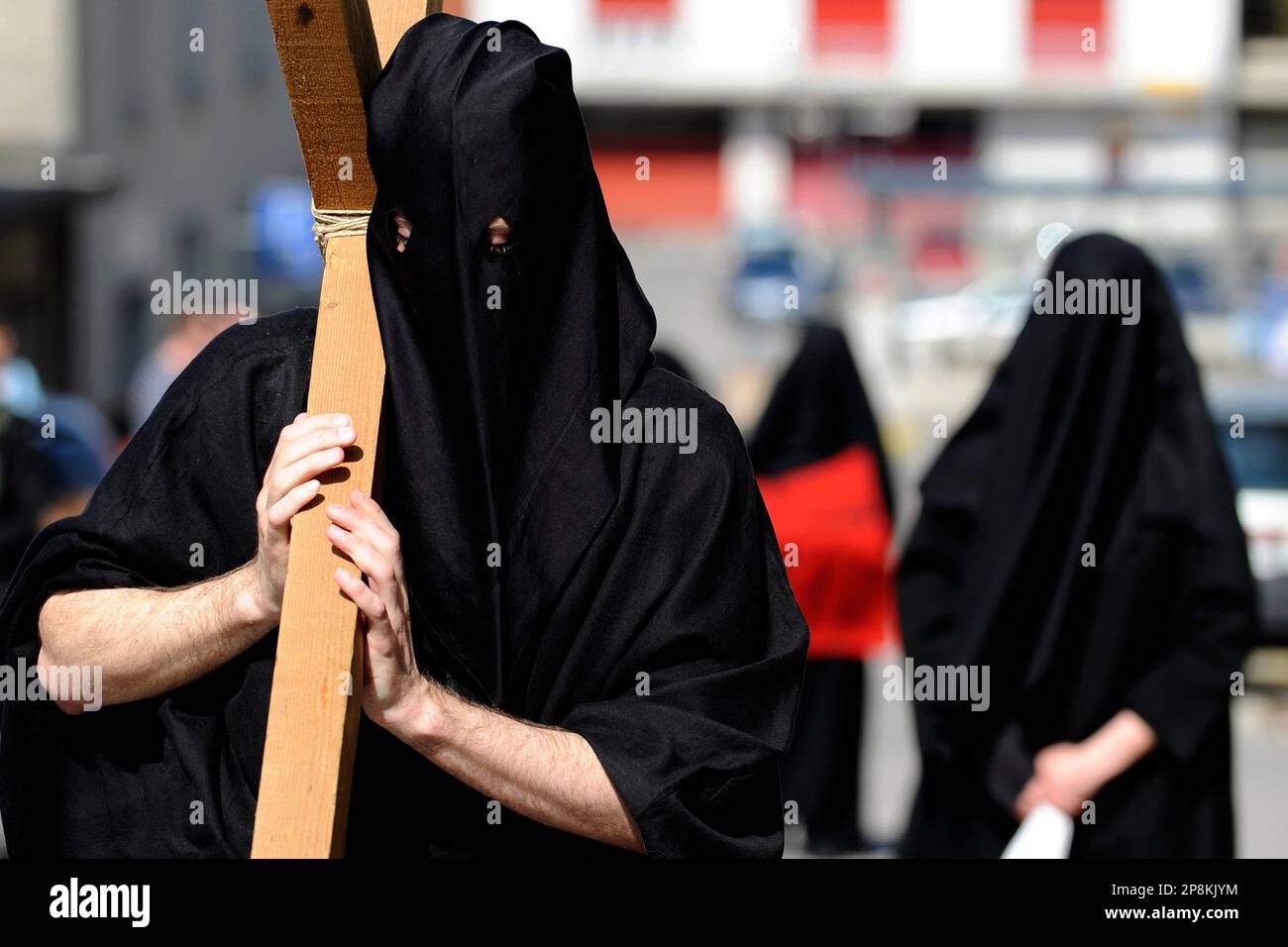 A cross bearer, whose head is covered with a piece of black cloth is ...