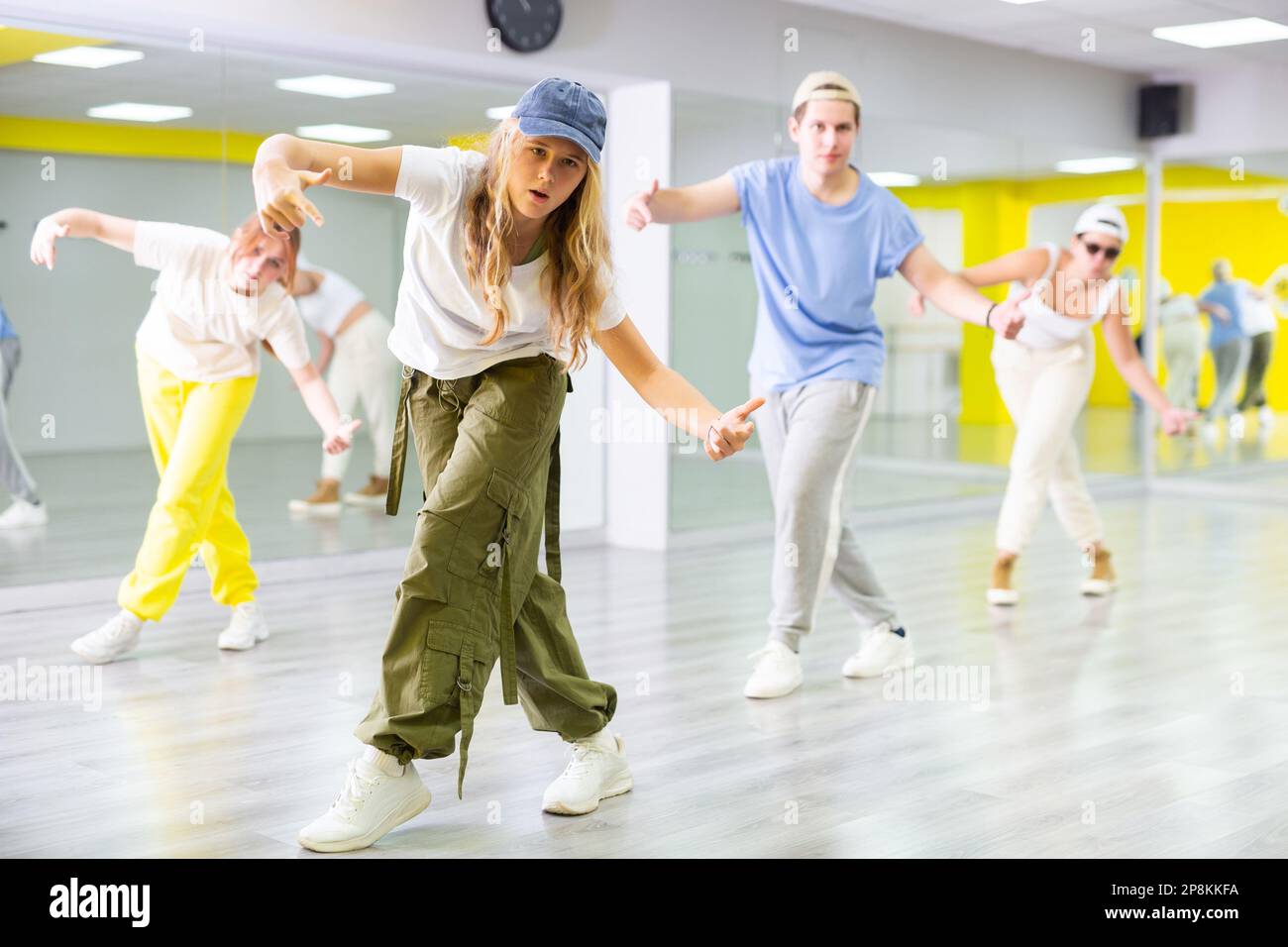 Teenage girl in cap training breakdance Toprock moves in dance hall ...