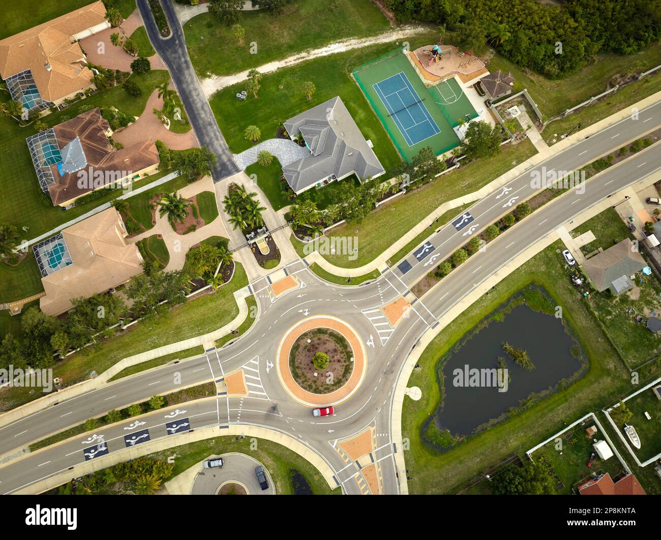 Aerial view of american suburban area with rural road roundabout intersection with moving cars ...