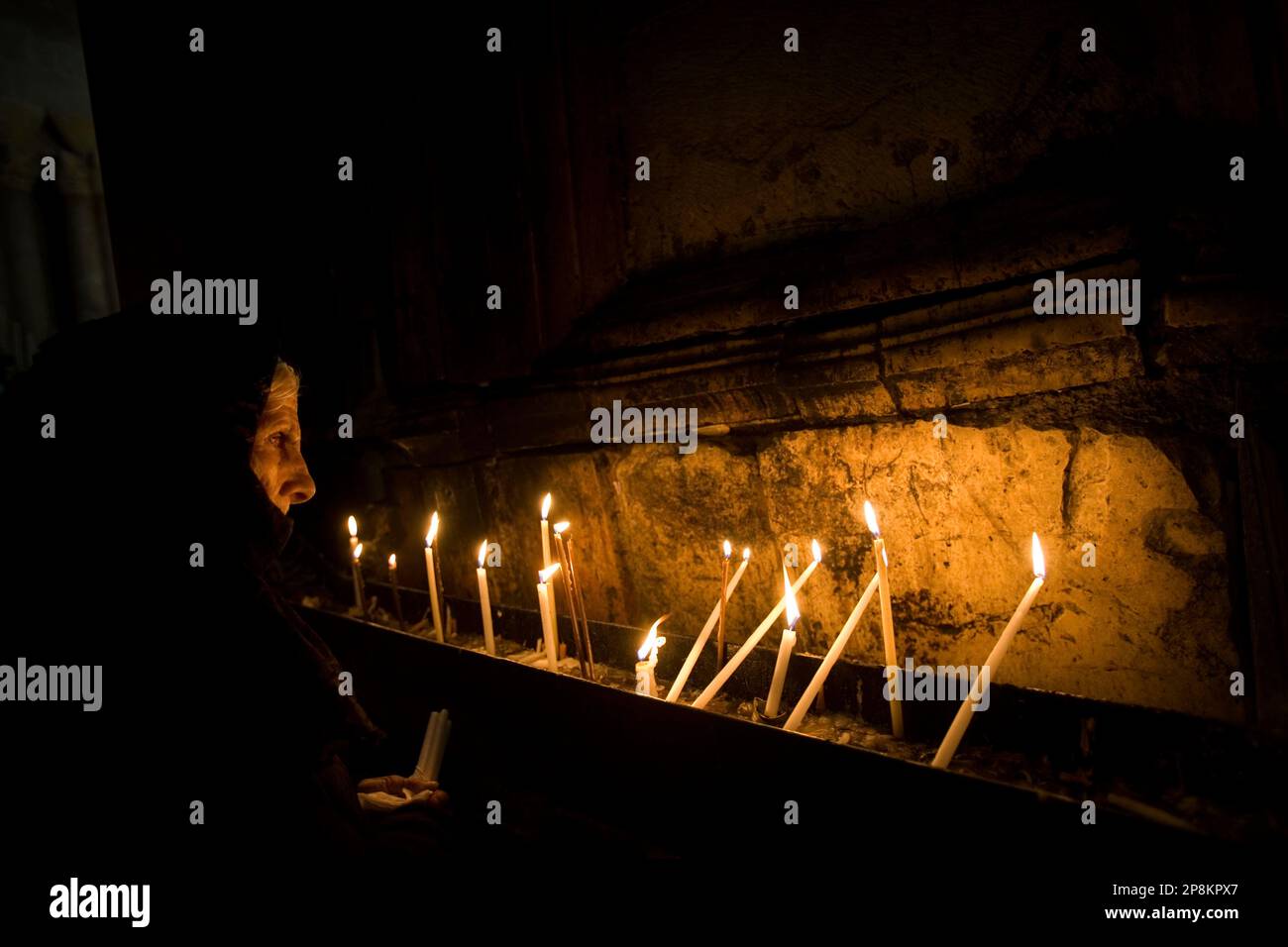 A Christian worshipper lights candles outside the Edicule, the site ...