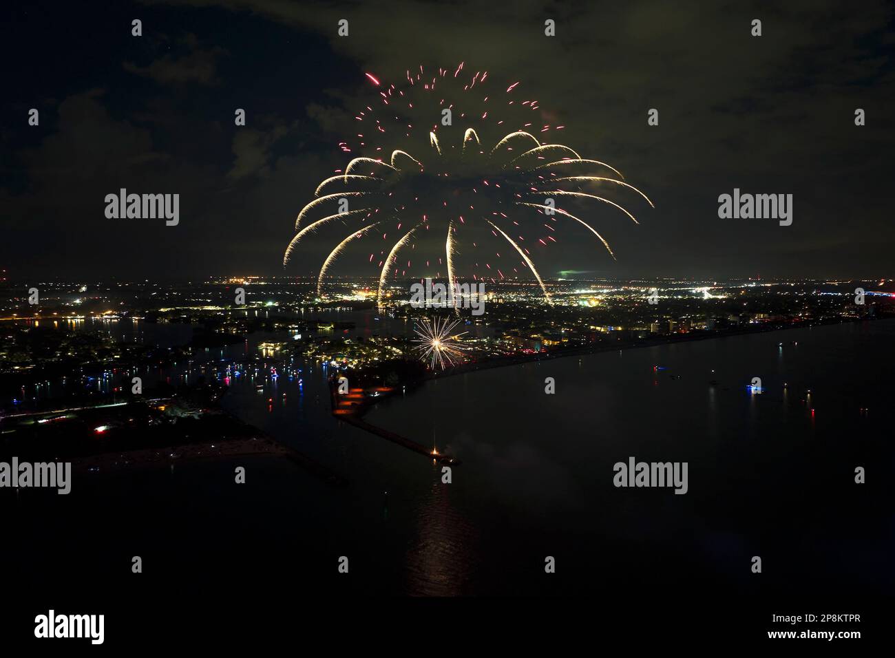 Aerial view of bright fireworks exploding with colorful lights over sea ...