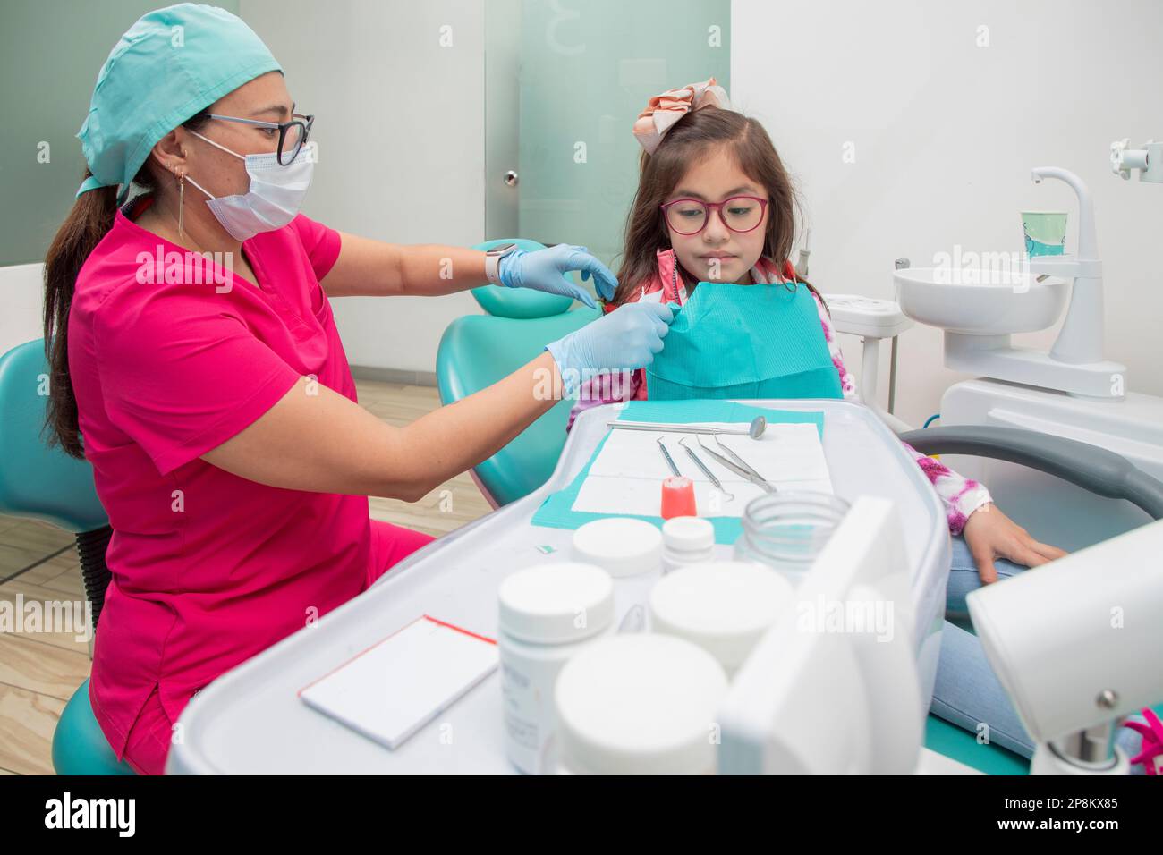 Female dentist with a young girl in her office after dental treatment ...