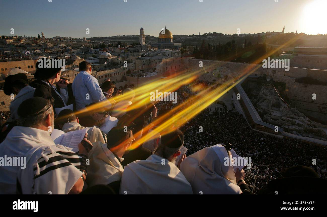 The sun flares across the scene as Ultra Orthodox Jewish men wrapped in ...