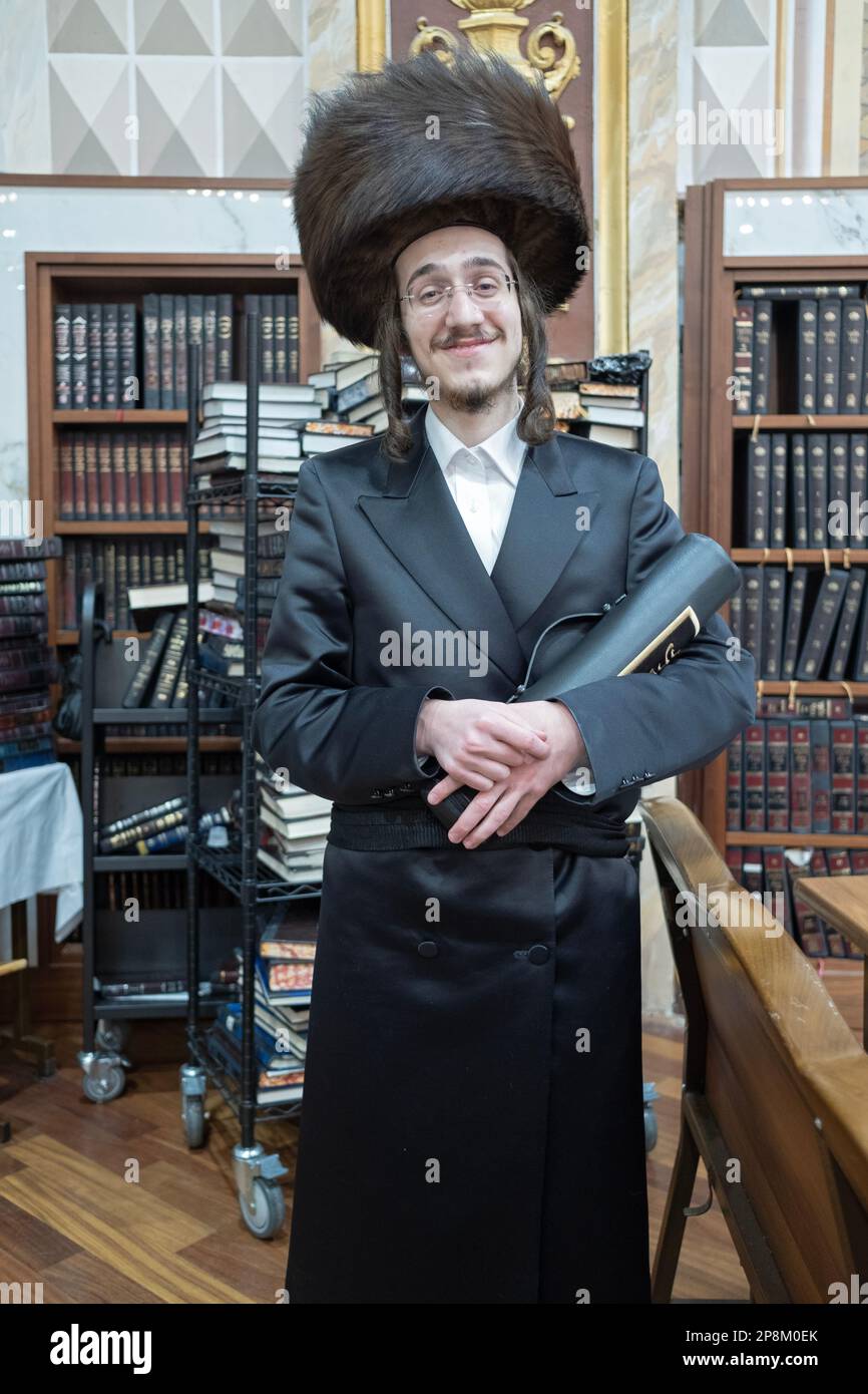 Posed portrait of an orthodox Jewish man wearing a streimel and holding ...