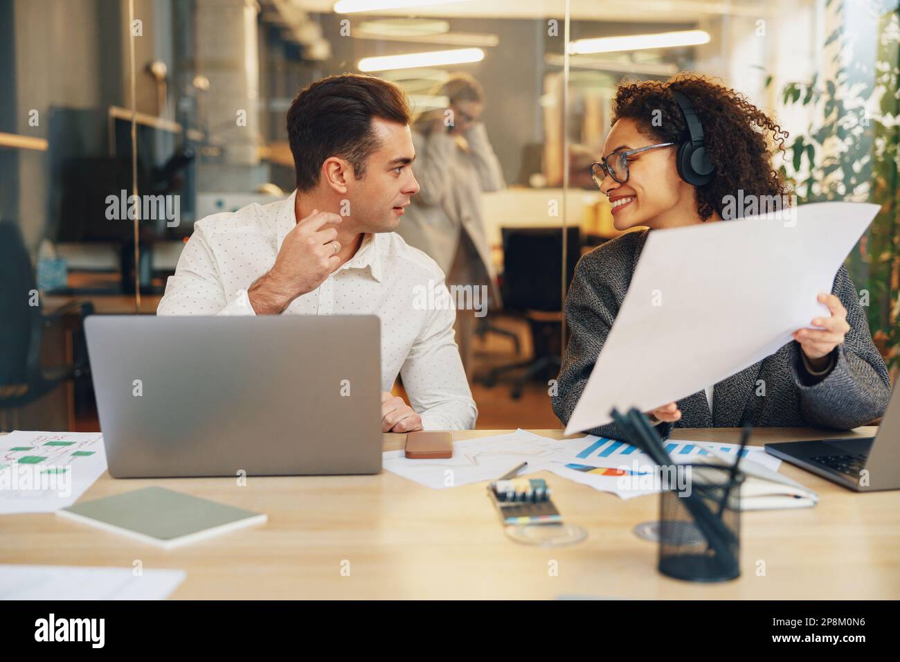 Two colleagues working together with documents while sitting on office ...
