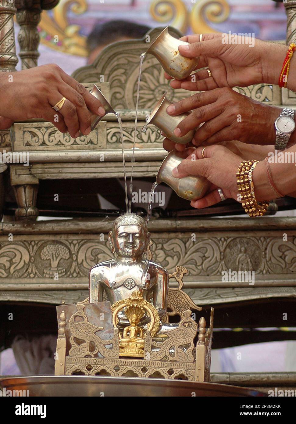 Jain devotees, only hands seen, perform rituals during the celebration ...