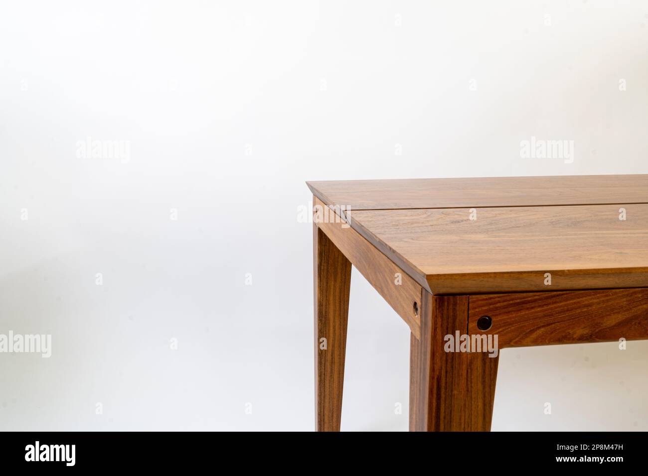 A detail of a rectangular wooden table isolated in a white setting ...