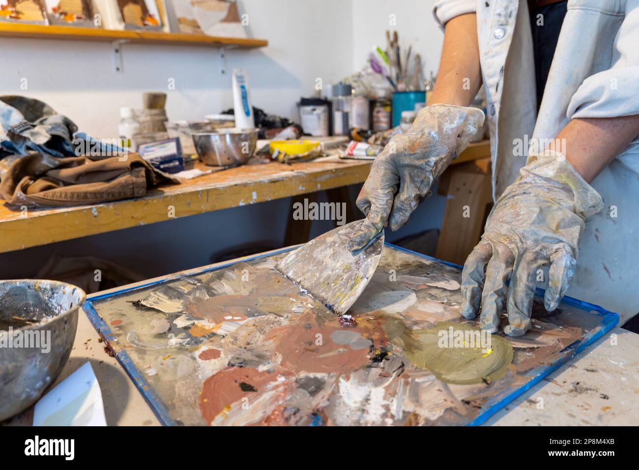 An artist creating artwork in an art studio interior lit by natural ...
