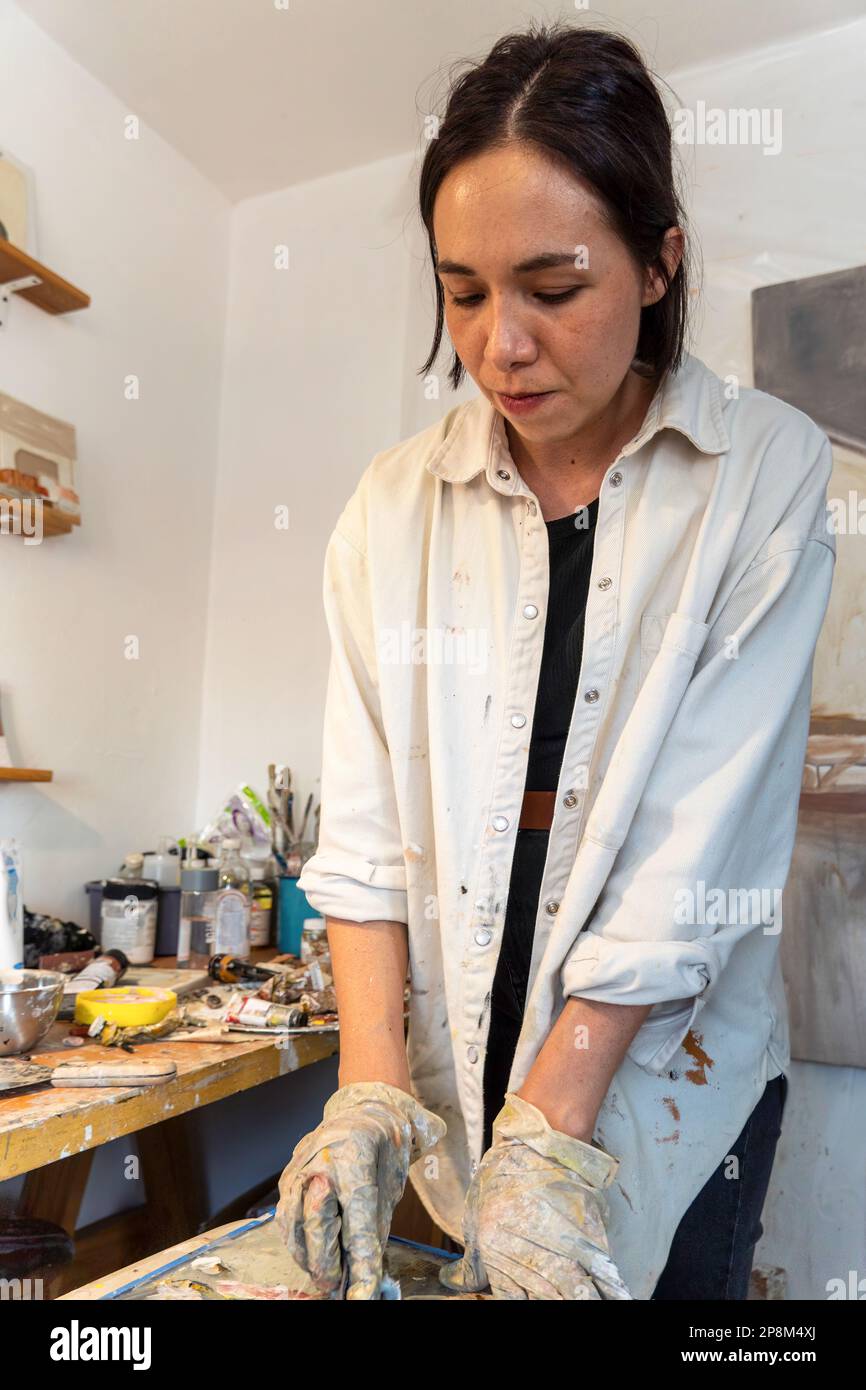 A vertical shot of a woman creating artwork in an art studio interior ...