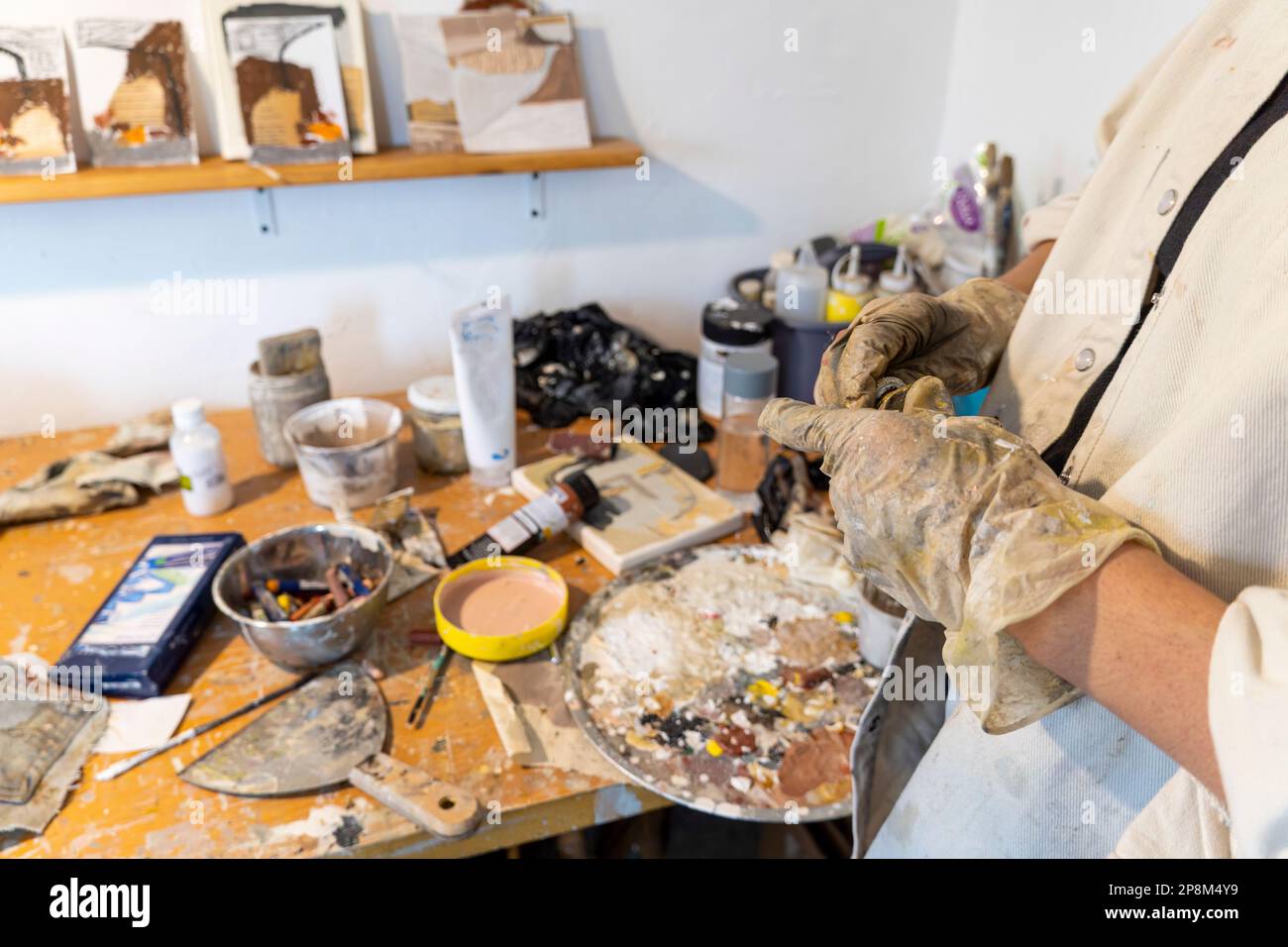 A woman artist creating artwork in an art studio interior lit by ...