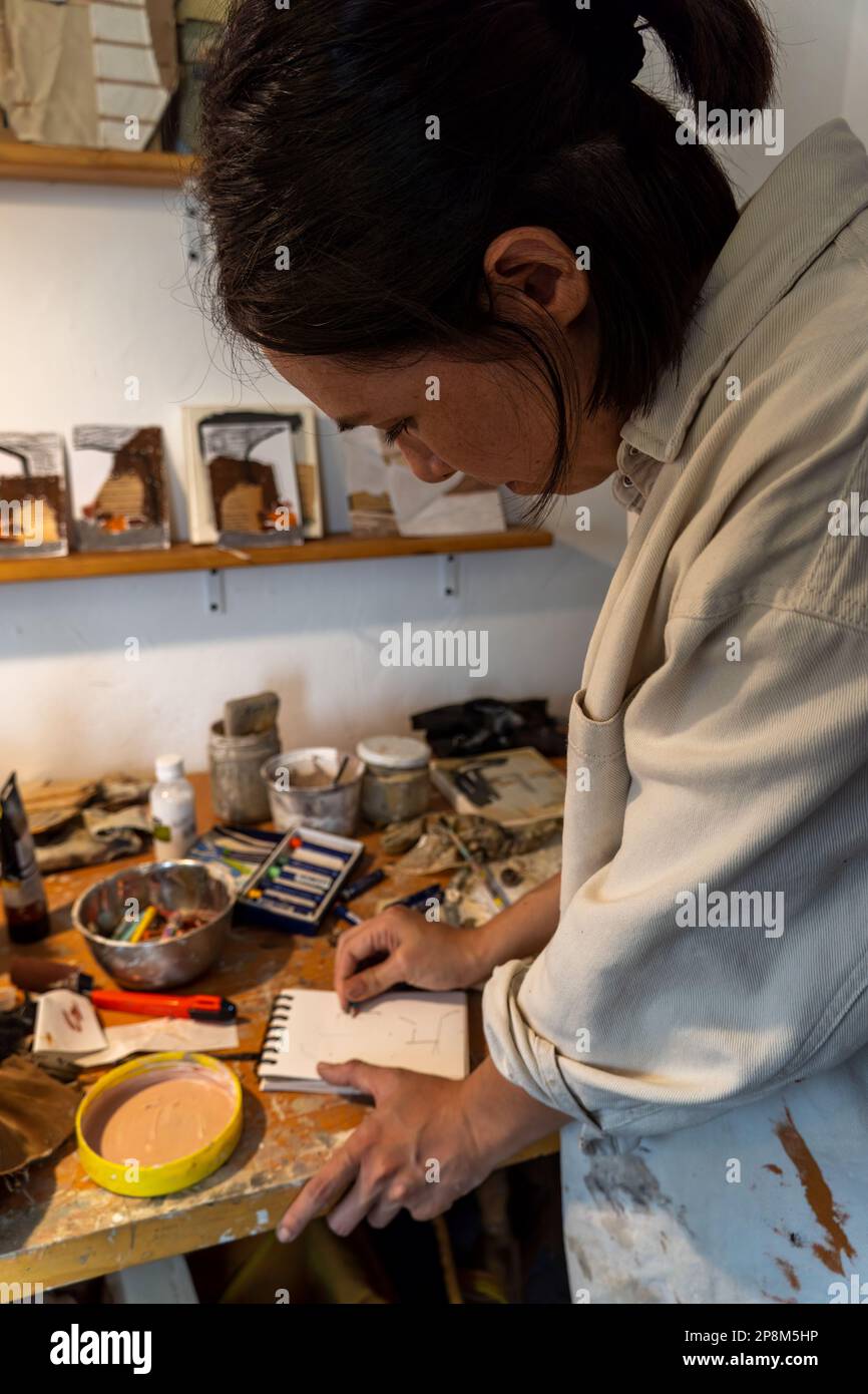 A vertical shot of a woman creating artwork in an art studio interior ...