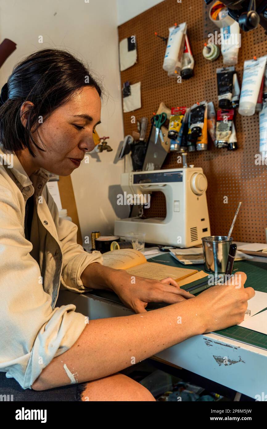 A vertical shot of a woman creating artwork in an art studio interior ...