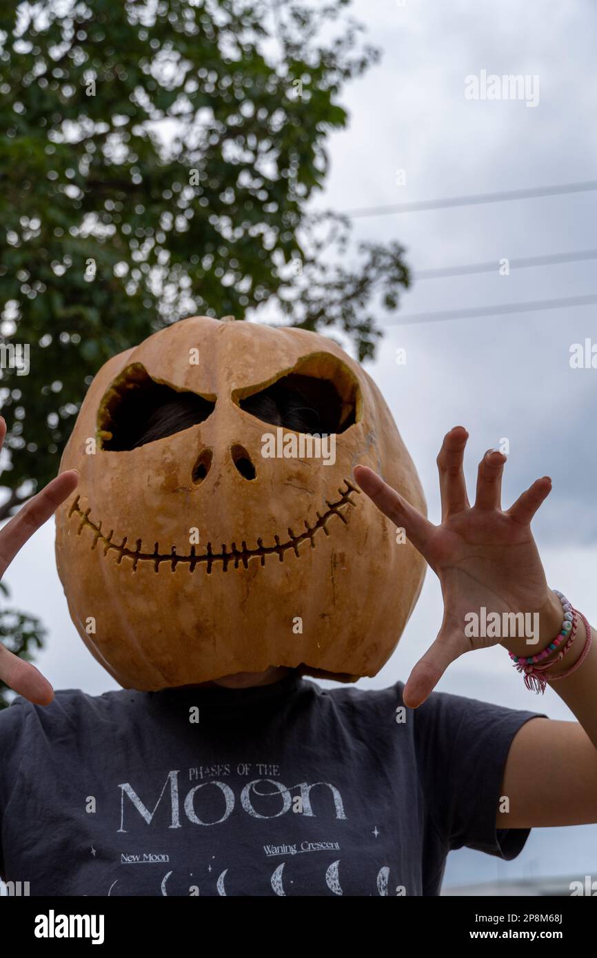 A woman with a pumpkin mask on her head striking a spooky pose for ...